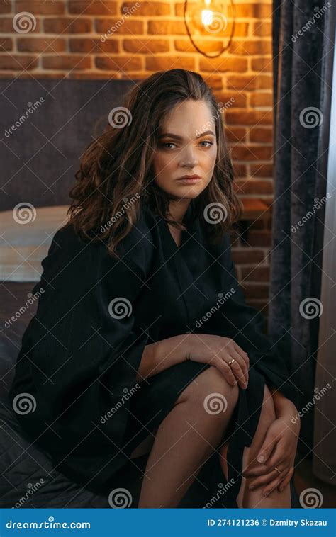 Portrait Of A Beautiful Woman In A Black Bathrobe Who Is Sitting On