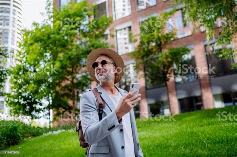 밀짚 모자와 배낭을 착용하고 전화를 사용하는 자신감있는 남자 여름철 캐주얼 한 옷을 입은 사업가가 출근합니다 균형에 대한 스톡 사진 및 기타 이미지 Istock