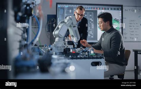 Concentrated Teacher Helping Asian Engineer Student Working With