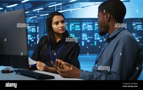 Coworkers In Data Center Looking Over Annual Systems Review Documents Discussing About