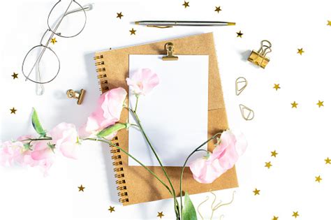 데스크톱 모형 장면입니다 사무실 장비가 장착 된 흰색 작업 테이블 배경의 상단 보기 플랫 레이 글래스 꽃 황금 종이 바인더 클립 빈 인사말 카드 공예 노트북 및 펜 0명에