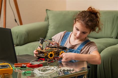 Young Girl Working On A Robotics Project Carefully Connecting Wires And Using A Multimeter