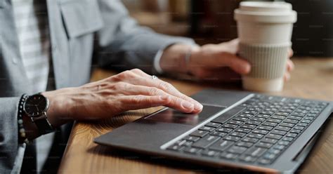 젊은 사업가 또는 프리랜서가 카페에 앉아 새로운 프로젝트를 진행하는 동안 커피를 마시는 노트북 키보드 위에 있다 사진