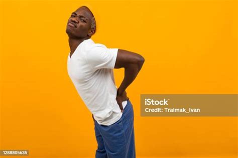 잘 생긴 매력적인 흑인 남자 흰색 티셔츠에 그의 등을 마시는 노란색 고립 된 배경에 복사 공간 20 24세에 대한 스톡 사진 및 기타 이미지 Istock