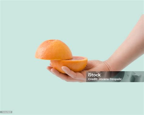 여자 손은 청록색 녹색 파란색 배경에 그녀의 손에 빨간 자몽의 두 반쪽을 들고 있습니다 여름 건강 과일 개념입니다 감귤류 과일에 대한 스톡 사진 및 기타 이미지 Istock