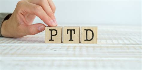 A Hand Is Touching A Wooden Block With The Letters Ptd On It Stock