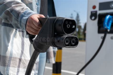 Woman Holding CCS Fast Charging Socket Type Plug For Electric Vehicles At EV Car Charging