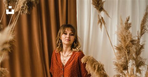 빨간 스웨터와 흰 바지를 입은 여자가 녹색 식물 옆에 서 있다 사진 Unsplash의 무료 갈색 이미지