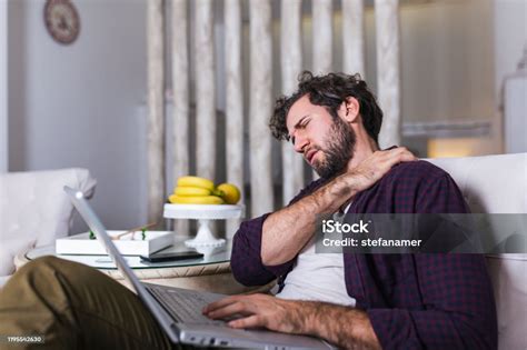 그의 어깨에 통증 상완 통증 신체 근육 문제가있는 사람들 건강 관리 및 의학 개념 매력적인 젊은 남자는 소파에 앉아 다른 손으로 고통스러운 어깨를 들고 남자에 대한 스톡