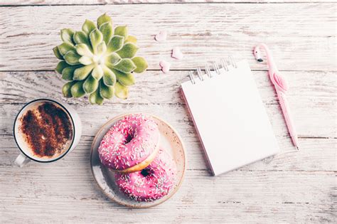 홈 오피스 데스크 계획 쓰기 또는 스케치 개념 빈 페이지 커피 한 잔과 흰색 소박한 나무 배경에 분홍색 장식으로 덮여 도넛 오픈