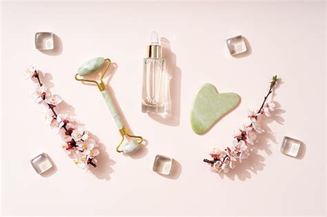 얼굴을위한 화장품 배경 롤러 노화 방지 구아샤 스크레이퍼 스킨 케어 셀프 케어 세트 파스텔 핑크 배경입니다 옥 보석에 대한 스톡