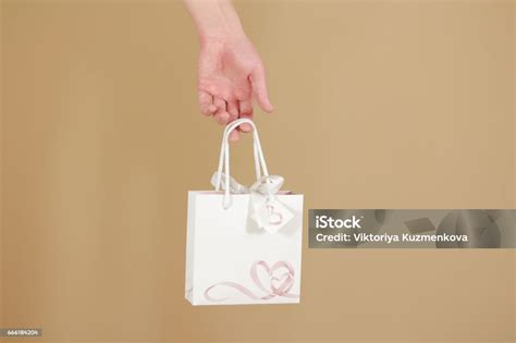 하트가 있는 빈 백종이 선물 가방이 손에 들고 있는 것을 조롱합니다 빈 플라스틱 패키지 모형은 고립된 손에 잡습니다 로고 디자인 또는 아이덴티티 프리젠 테이션을위한 소비자