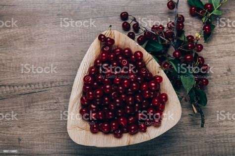 나무 테이블에 나무 접시에 신선한 빨간 체리 나무 접시 그것에 나무 Backgroundnext에 체리와 녹색 잎 벚꽃 지점 이다 삼각형의 형태로 접시입니다 생태학입니다 적절