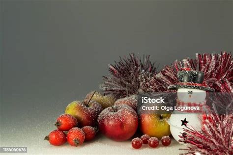 잘 익은 아름다운 사과와 과일은 촛불 노트북 딸기 눈사람 화환 홍채 장미 엉덩이와 함께 크리스마스 공 눈 속에서 회색 배경에