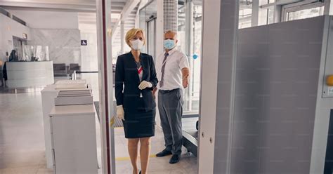 의료 마스크를 쓴 매력적인 사업가가 체크인 게이트를 통과하는 동안 남성 공항 직원이 그녀 뒤에 서 있다 사진 Unsplash의 사람 이미지