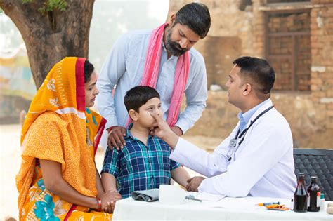 인도 의사는 마을에서 어린 소년 환자를 검사하고 남편과 아들과 함께 사리를 입은 여성 시골 인도 의료 개념을 검사합니다 30 34세에 대한 스톡 사진 및 기타 이미지
