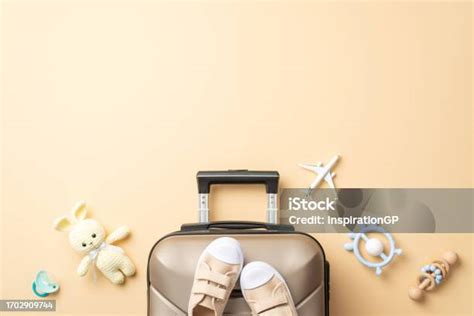 신생아의 첫 비행 파스텔 베이지색 배경에 소형 비행기 모델 여행 가방 젖꼭지 니트 토끼 장난감 나무 딸랑이 치발기 작은 부츠의 평면도 프로모션 메시지를 위한 멋진 공간 0