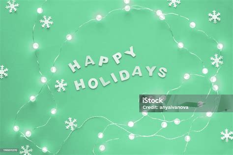 새해 또는 크리스마스 패턴 플랫 텍스트 해피 홀리데이와 상단보기 배경을 누워 네오 민트 녹색 배경에 종이 눈송이와 축제 조명의 화환 트렌디 한 흑백 착색 배경입니다 즐거운