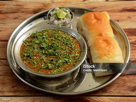 파브 바지는 인도의 패스트푸드 요리로 두껍고 매운 채소 카레로 부드러운 롤빵이나 분 파브 버터를 곁들인 요리입니다 소박한 나무 배경 선택적 초점 위에 고립 Pav Bhaji