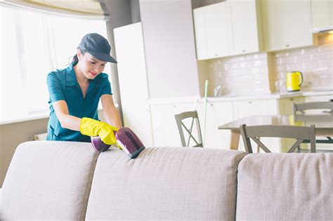 소파의 가장자리를 청소 하는 소녀의 사진 그녀는 작은 진공 청소기를 사용 합니다 여성은 전문적입니다 그녀는 완벽 하 게 작동