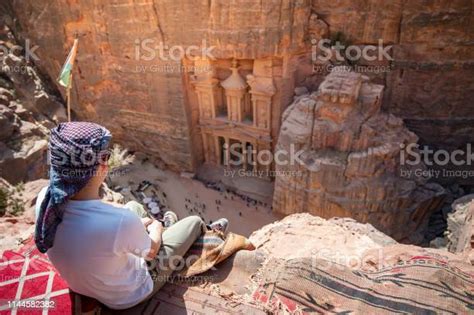 페트라 고 대 도시의 카펫 전망대에 앉아있는 아시아 남성 여행자는 재무부 또는 알 카 즈 네 요르단의 유명한 여행 목적지와 일곱 불가사의 중 하나를 보고 있다 유네스코 세계