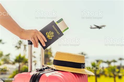 분홍색 가방과 아메리안 여권을 소지한 여성은 야자수가 있는 바다 맞은편 비행기 사다리에 탑승권을 소지하고 있습니다 관광 컨셉