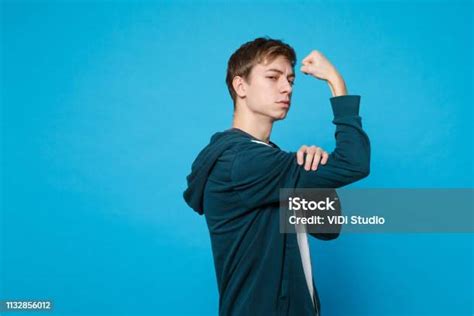 캐주얼에 자신감 젊은 남자의 초상화 감동 팔 뚝 스튜디오에서 파란색 벽 배경에 고립 된 근육을 보여주는 사람들은 진심으로 감정 라이프 스타일 개념입니다 복사 공간을 모의