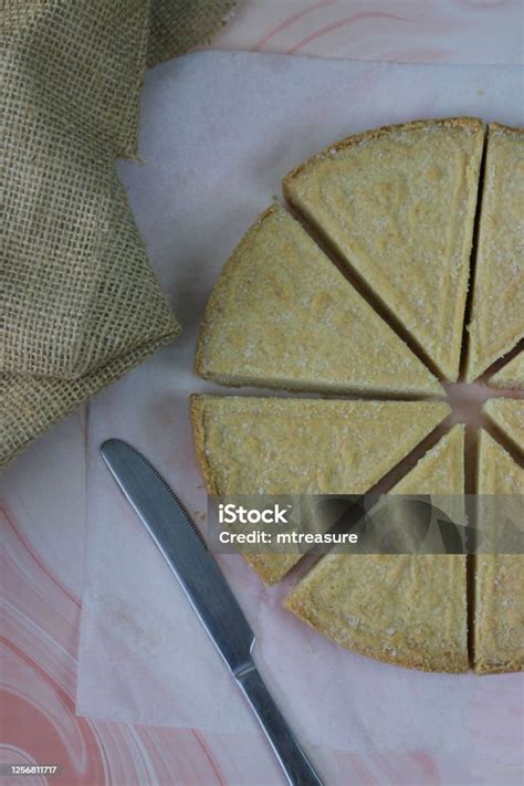 엉겅퀴 금형 패턴 디테일을 보여주는 슬라이스 버터 수제 쇼트 브레드 라운드의 이미지 오븐에서 신선한 황금 갈색 회색 차 수건과 칼 핑크 대리석 효과 배경 높은 전망 외에