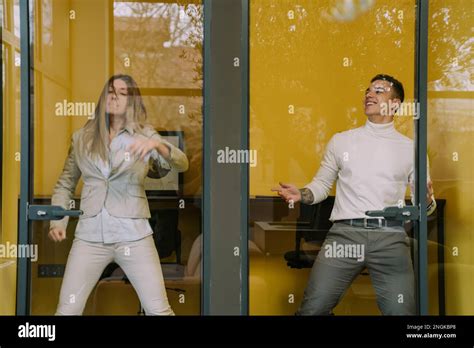 Two Business Colleagues Goofing Off And Dancing In The Phone Booths At