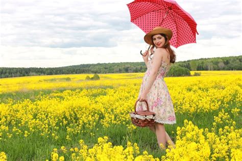 Девушка в поле цветков с зонтиком и шляпой Стоковое Фото изображение