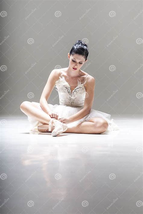 Молодая привлекательная балерина сидя на поле работая с ей указала