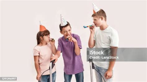 생일 모자를 쓰고 서로를 바라보며 휘파람을 불며 흰색 배경위에 고립된 생일을 축하하는 세 명의 장애아동 파티에 대한 스톡 사진 및 기타 이미지 Istock