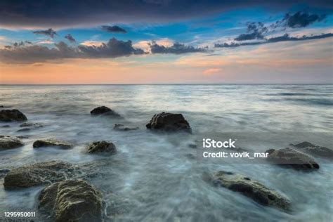일몰에 바다의 놀라운 풍경 드라마틱한 하늘 파도 바위 투성이의 바다 해변의 다채로운 저녁 전망 긴 노출 이미지 바다 풍경의 개념