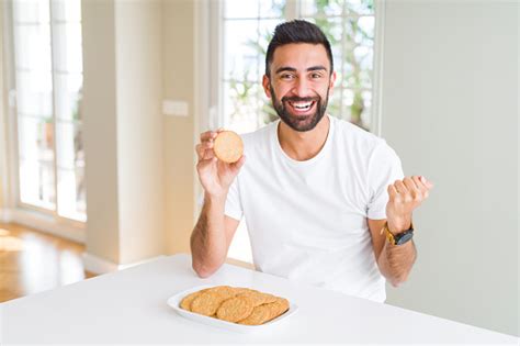 잘 생긴 히스패닉 남자 먹고 건강 한 통곡물 비스킷 자랑 하 고 승리와 성공을 축 하 매우 흥분 응원 감정 감정에 대한 스톡