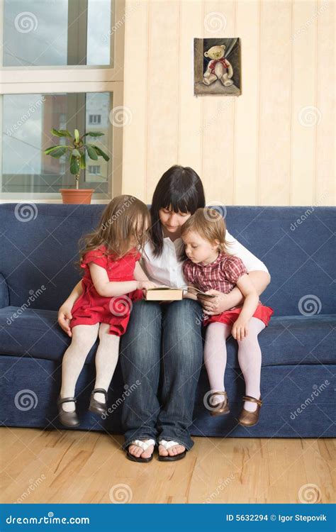 Sirva De Madre A Leer Un Libro Con Sus Pequeñas Hijas Foto De Archivo