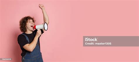 젊은 털이 많은 남자의 초상화와 전단지 분홍색 배경에 고립 된 메가 폰에서 외치는 검은 색 티셔츠를 입은 학생 20 24세에 대한 스톡 사진 및 기타 이미지 Istock