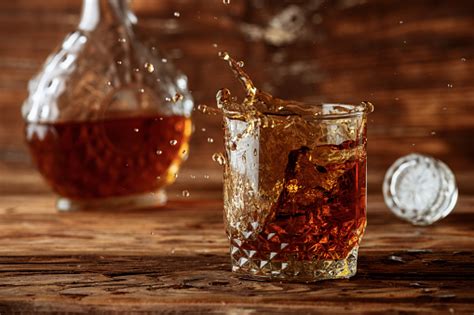 코냑 위스키 또는 브랜디 한 잔에 쓰러진 얼음 조각에서 튀어 나온 갈색 나무 테이블에 알코올 음료가 있는 병의 배경에 대해 각얼음에 대한 스톡 사진 및 기타 이미지 Istock