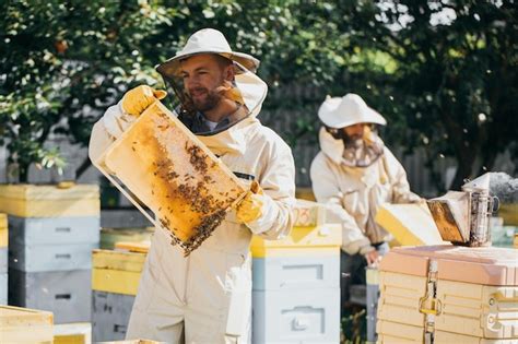 Premium Photo Two Beekeepers Works With Honeycomb Full Of Bees In Protective Uniform Working