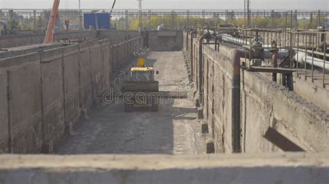 Excavator Carries Concrete Beam Passing In Basin Of Concrete Tank Stock