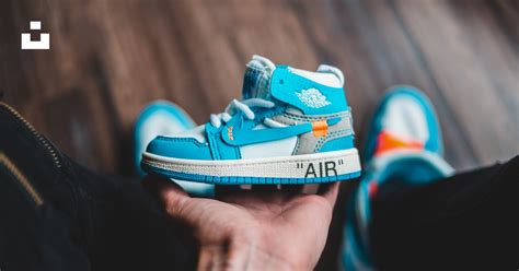 녹색과 흰색의 나이키 에어 조던 1을 들고 있는 사람 사진 Unsplash의 무료 의류 이미지