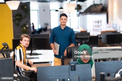 다민족 스타트업 비즈니스 팀 인 아라비아 여성이 노트북과 데스크톱 컴퓨터에서 작업하면서 현대 오픈 플랜 사무실 인테리어 브레인 스토밍에서 회의에 히잡을 착용하고 있습니다