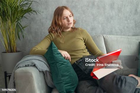 집에서 아늑한 소파에서 휴식을 취하는 슬픈 금발의 여자는 디지털 태블릿을 사용하여 영화를 스트리밍하거나 온라인 쇼핑을 한다 가정 생활에 대한 스톡 사진 및 기타 이미지