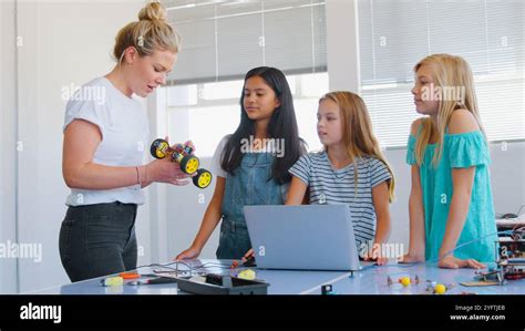 Teacher With Female Students Building And Programming Robot Vehicle In