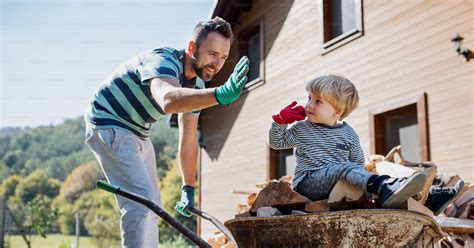 여름에 야외에서 행복한 아버지와 어린 소년이 손수레에 장작을 싣고 있습니다 사진 Unsplash의 사진술 이미지