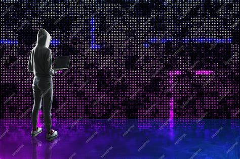 Premium Photo Hacker In Hoodie Holding Laptop And Standing On Abstract Glowing Pixel Wall
