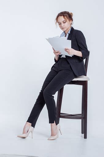 클래식 한 정장에 젊은 사무실 노동자 소녀는 흰색 배경에 고립 된 종이의 깨끗한 시트를 유지합니다 귀여운 금융가가 의자에 기대어 클립 보드를 손에 들고 직장에서 미리보기