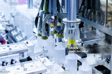 화장품 및 스킨 케어 제조에서 자동 캡핑 및 라벨링 기계의 컨베이어 벨트로 플라스틱 병을 이동하는 로봇 팔 화장품 산업 및 Ai 기술 기계 개념 화장품에 대한 스톡 사진 및