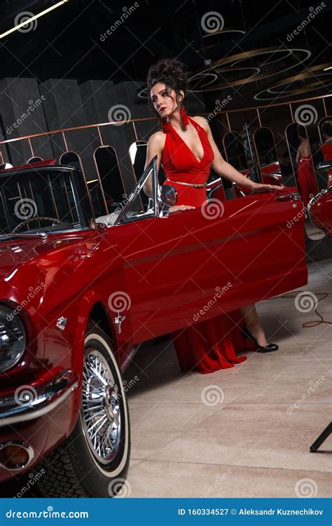 Girl In A Red Dress Posing On A Background Of Red Cars Stock Image