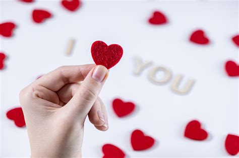 빨간 펠트 하트는 흰색 배경에 나무 글자 I Love You와 로맨스와 발렌타인 데이를 상징하는 흩어져있는 빨간 하트를 들고 있습니다 2월에 대한 스톡 사진 및 기타 이미지