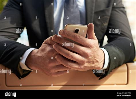 Sending A Text To The Office An Unrecognizable Businessman Sending A Text While Leaning On His
